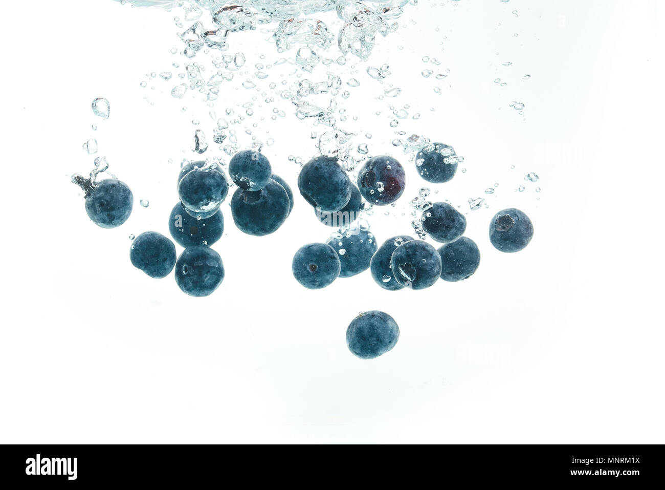 Blueberries sinking into water with air bubbles white background Stock ...