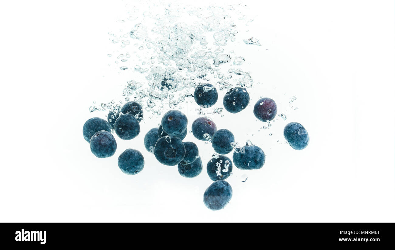 Blueberries sinking into water with air bubbles white background Stock ...