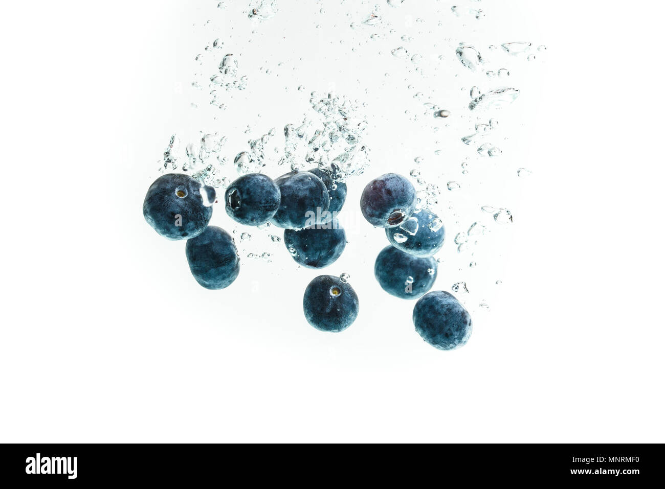Blueberries sinking into water with air bubbles white background Stock ...