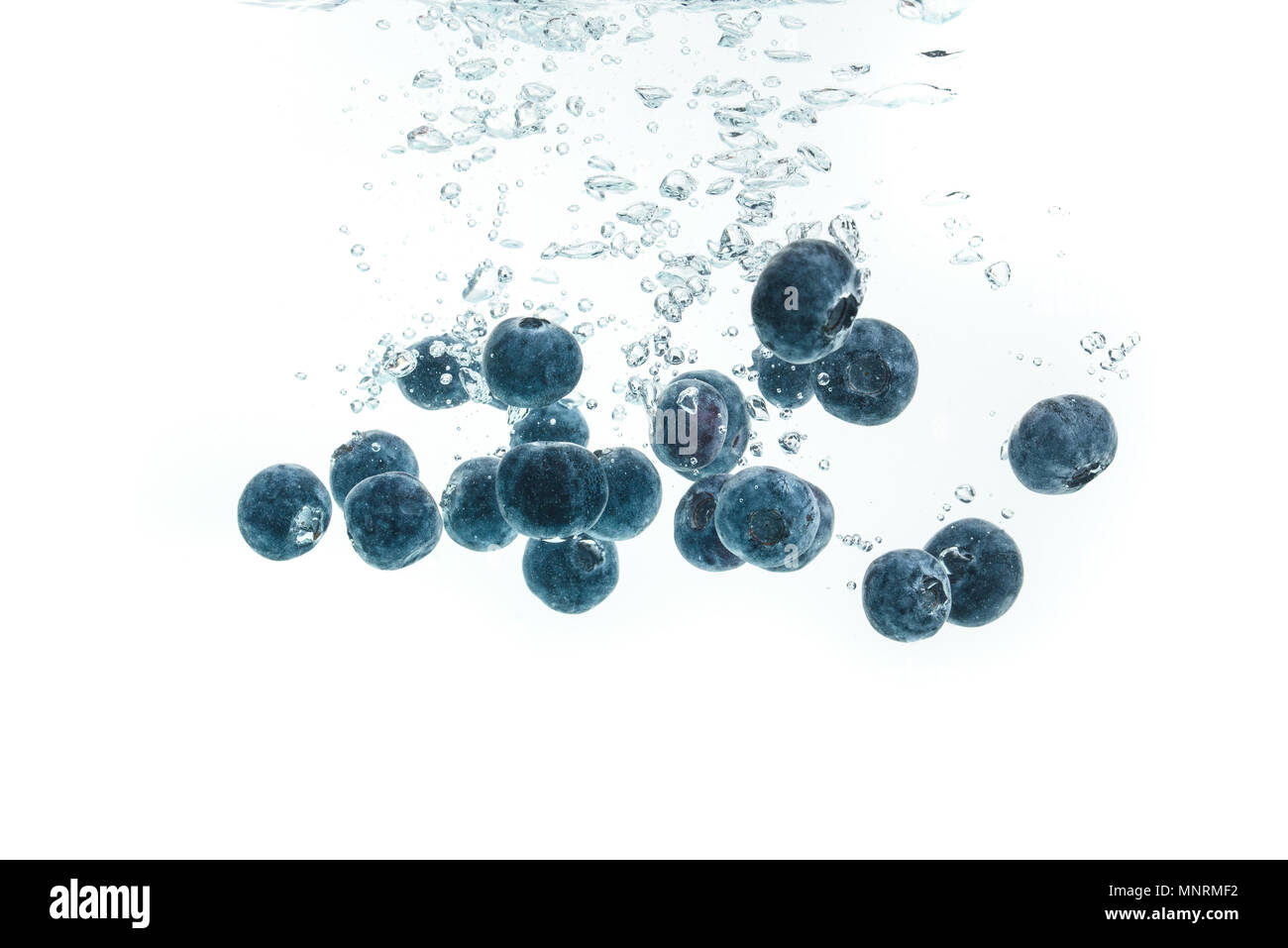 Blueberries sinking into water with air bubbles white background Stock ...