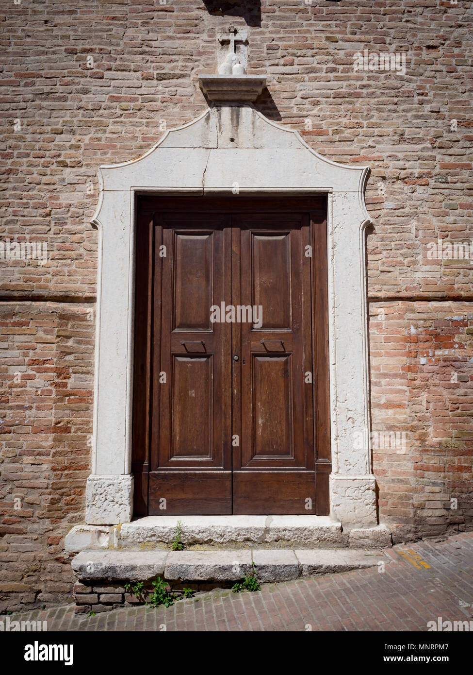 Entrance door of an old italian church with white stone outline on red ...