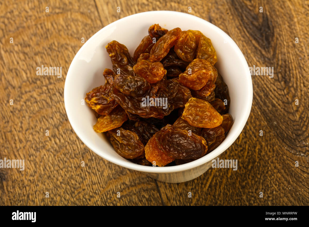 Dry Raisin in the bowl over the wooden background Stock Photo - Alamy