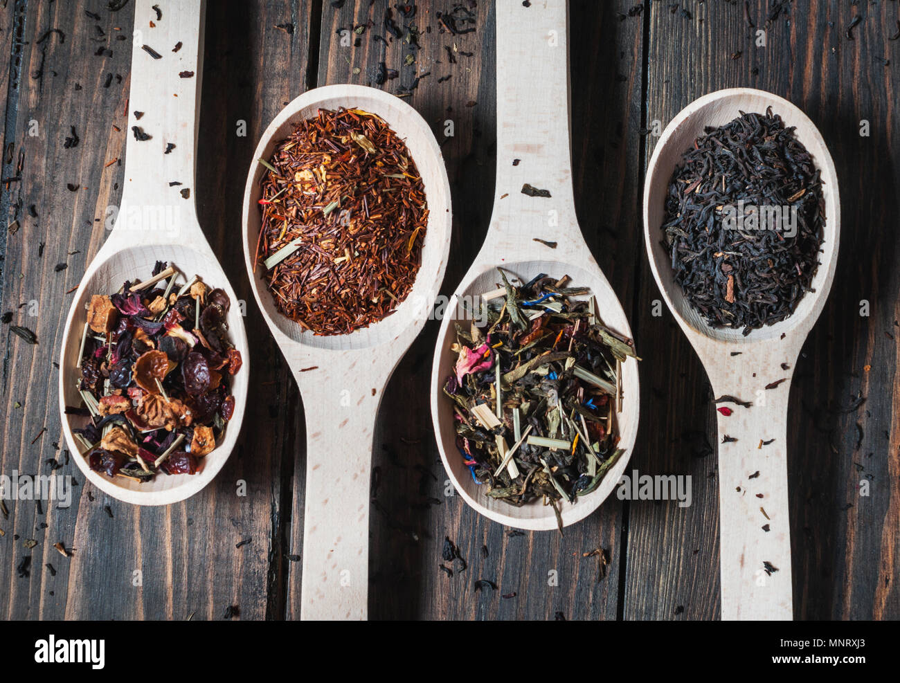 Different kinds of tea in wooden spoons on wood table. Top view Stock ...