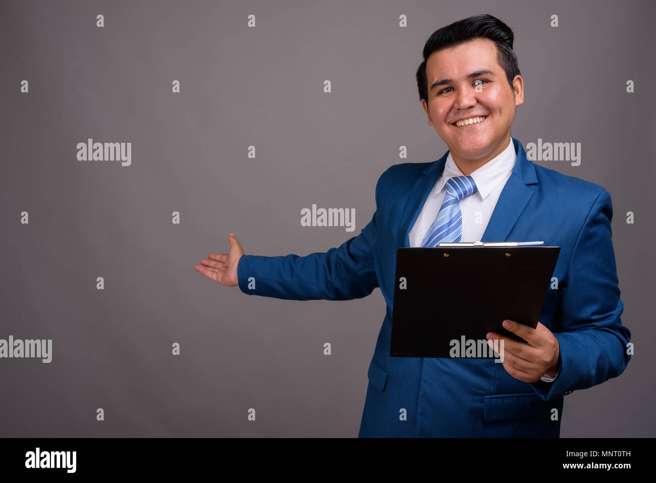 Young multi-ethnic businessman against gray background Stock Photo - Alamy