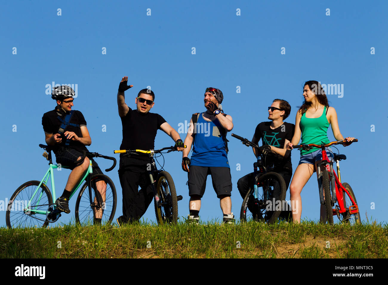 Group of young people, a man and a girl riding a bicycle in the city ...