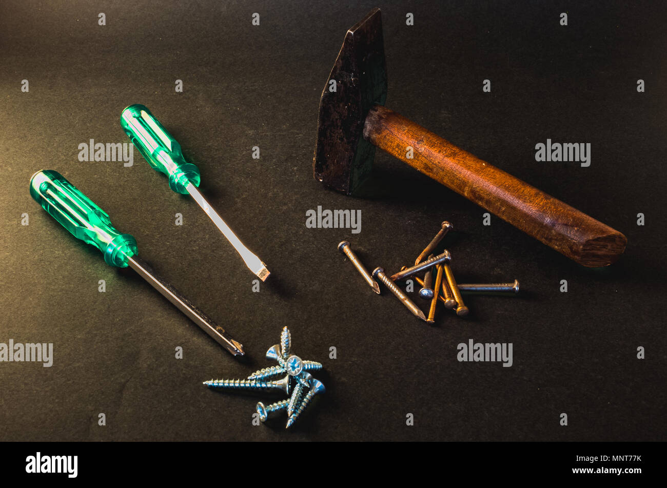 Screwdrivers, screws, nails and hammer on dark grey background Stock ...