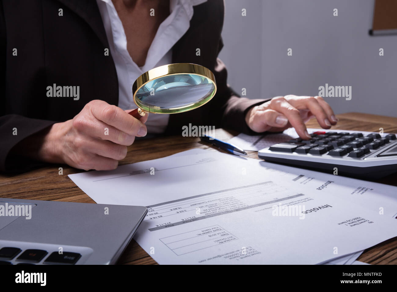 Businessperson's Hand Analyzing Invoice Through Magnifying Glass In ...