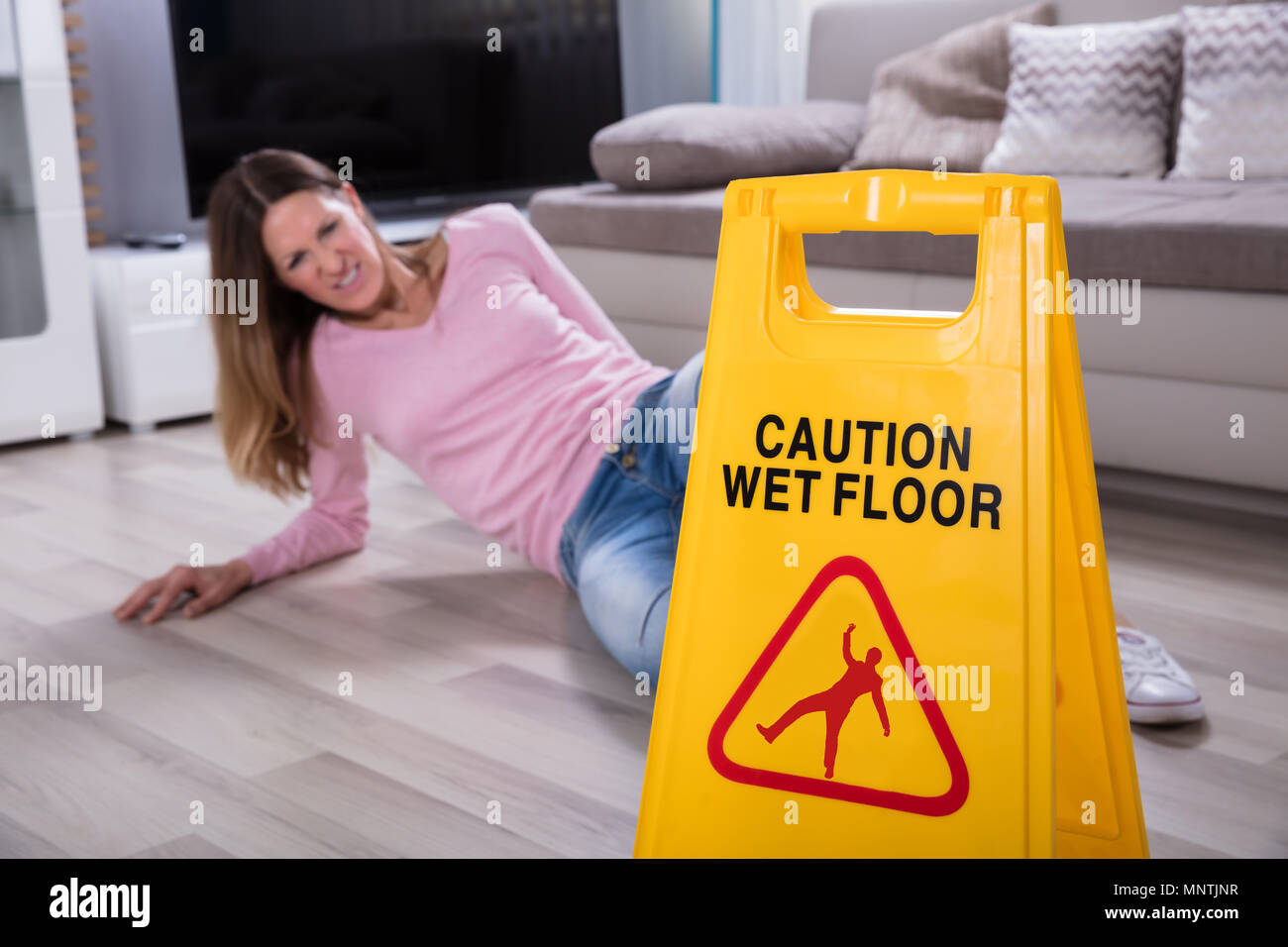 Mature Woman Falling On Wet Floor In Front Of Caution Sign At Home ...