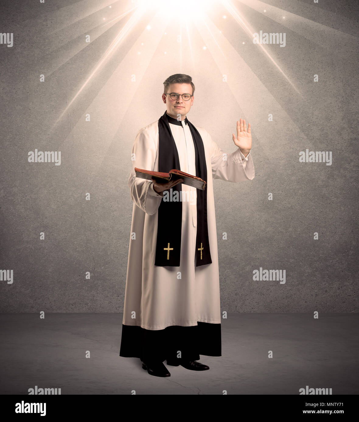 A male religious young priest in black and white dress giving his ...