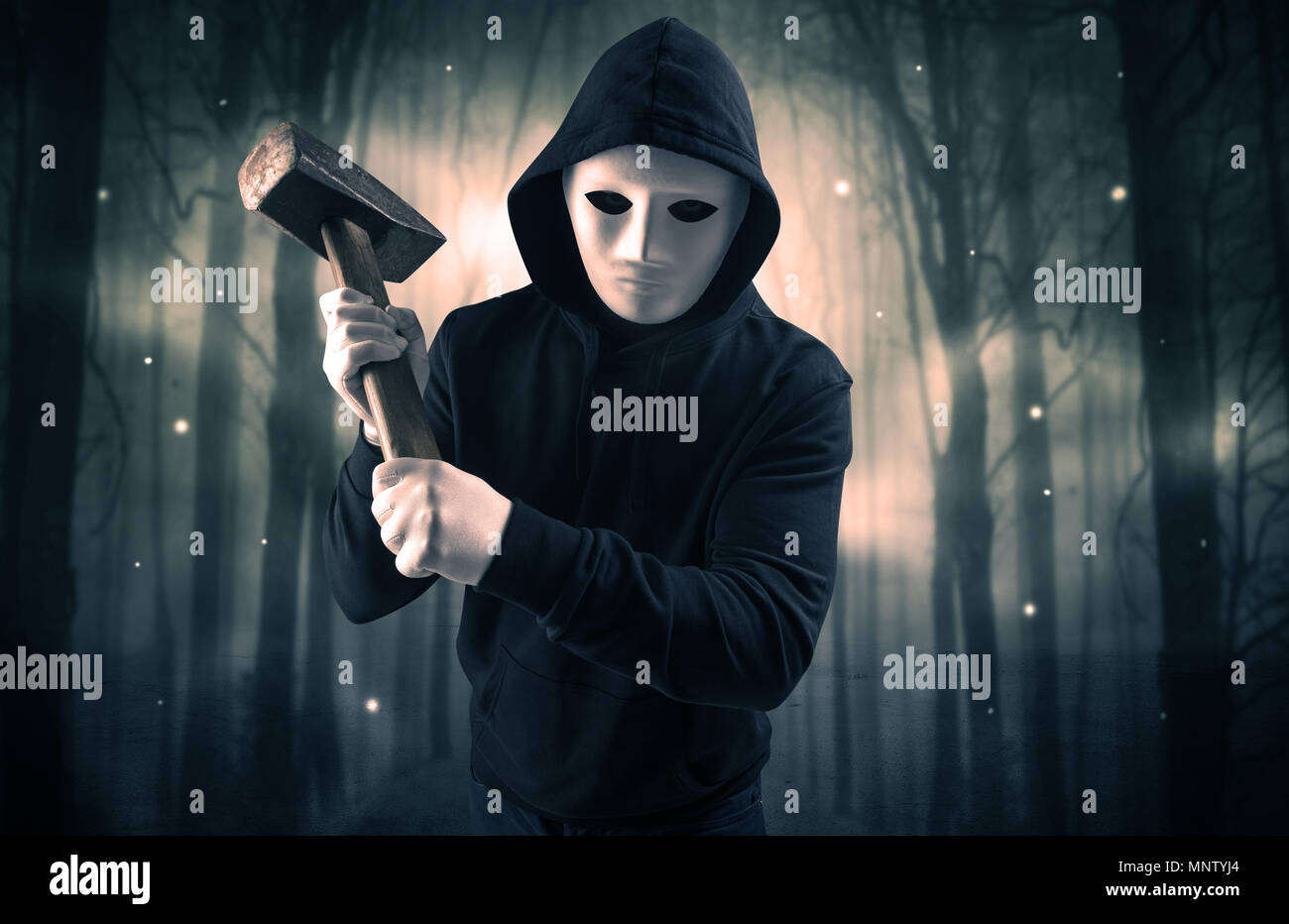 Masked armed hitman in dark thick forest with foggy mysterious concept ...