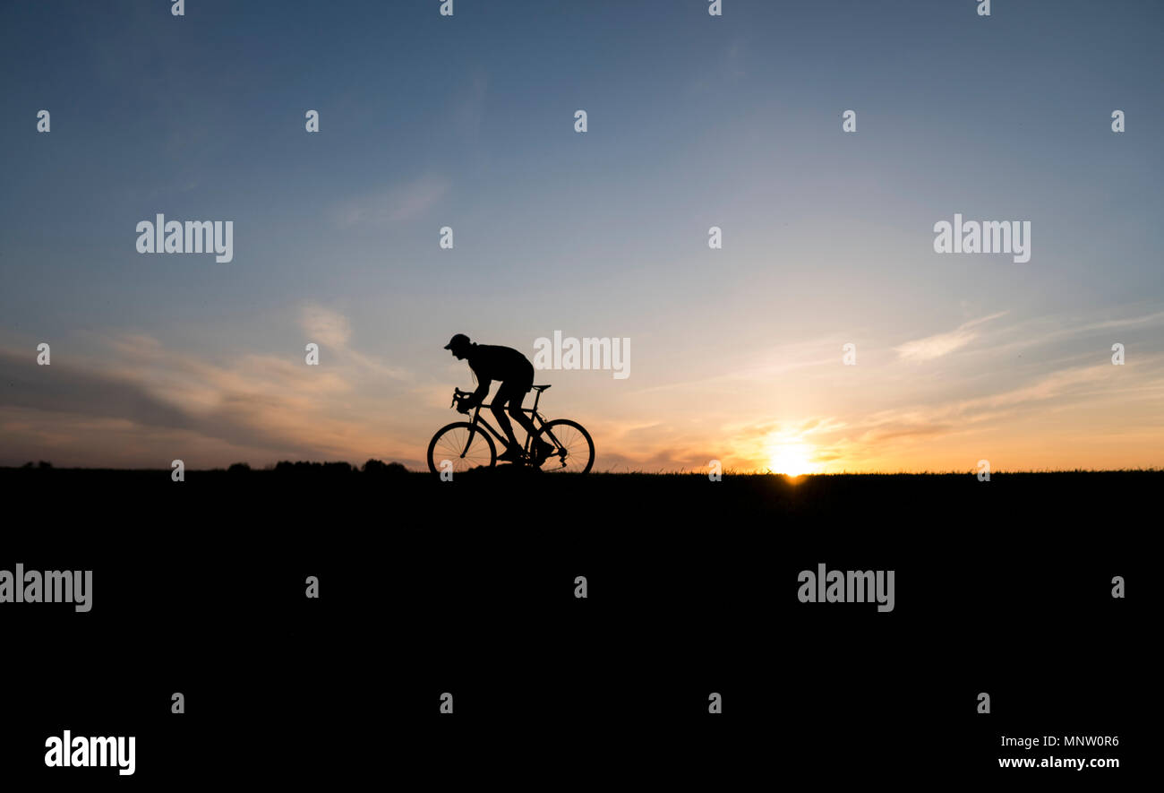 Silhouette of cyclist in motion on the background of beautiful sunset ...