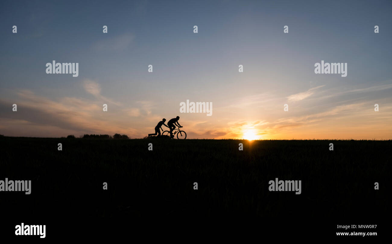 Silhouette of cyclist and running man without bike in motion on the ...