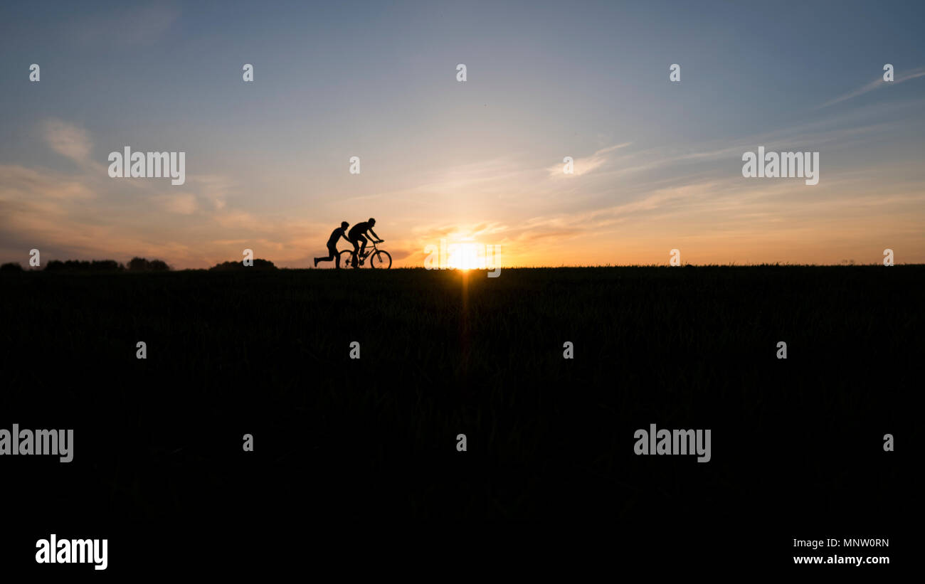Silhouette of cyclist and running man without bike in motion on the ...