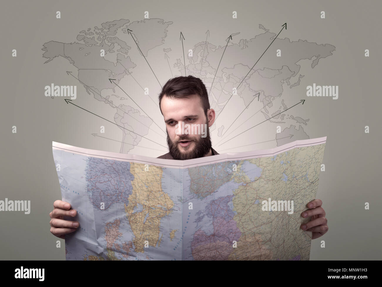 Handsome young man holding a map with world map and arrows behind him ...