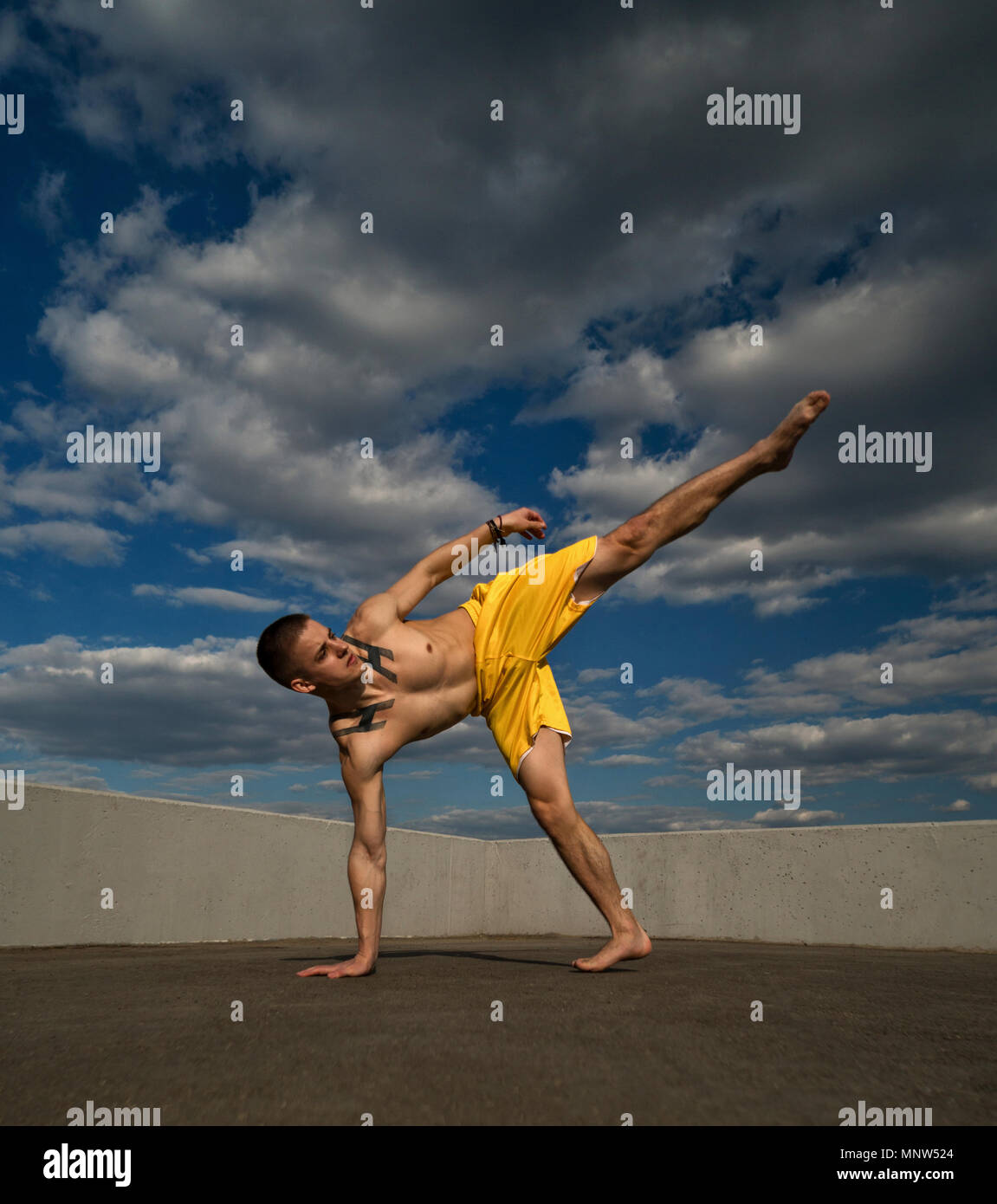 Tricking on street. Martial arts. Man kick with hand support barefoot ...