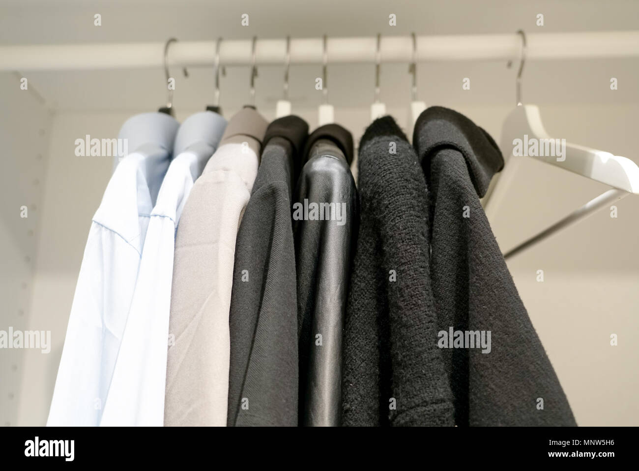 row of men and women shirts on the hanger, hanging in the wardrobe ...