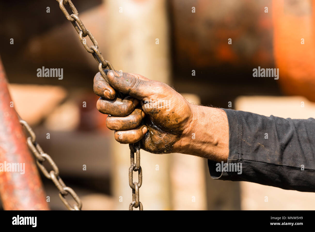 Worker at a shipyard in Dhaka Bangladesh holds a chain of a chain hoist ...