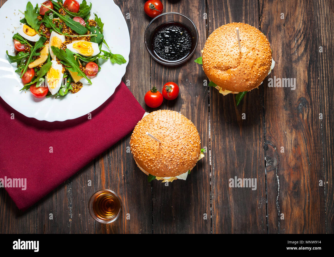 Fresh homemade burgers with a salad with arugula and alcohol on a dark ...