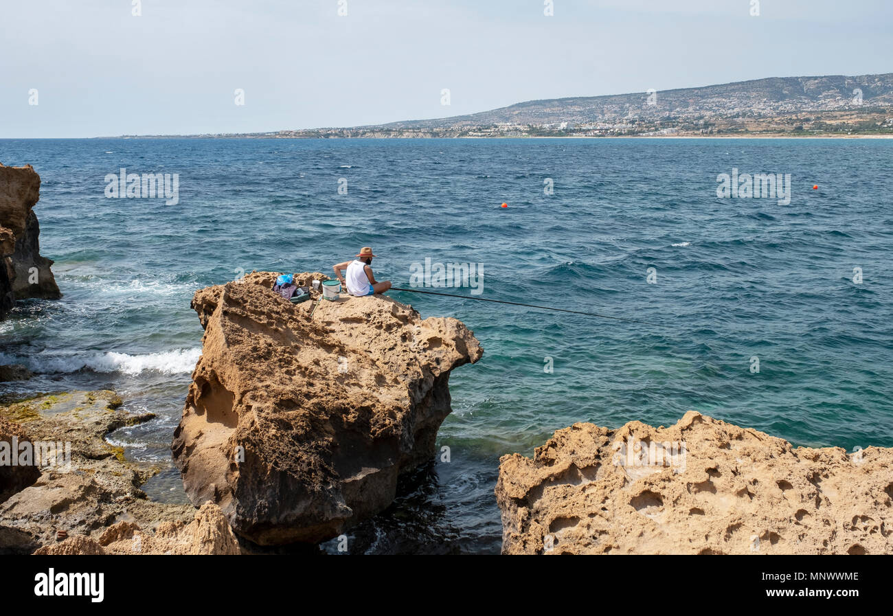 A man fishing from the rocks in the Coral Bay area, near Paphos, Cyprus ...