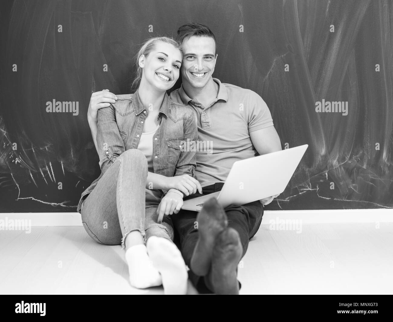 happy young loving couple using laptop computer in front of gray ...