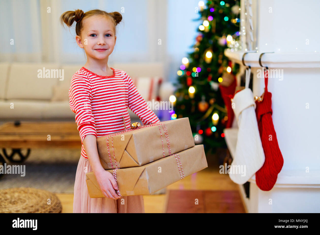 Adorable little girl holding Christmas presents in a beautifully ...