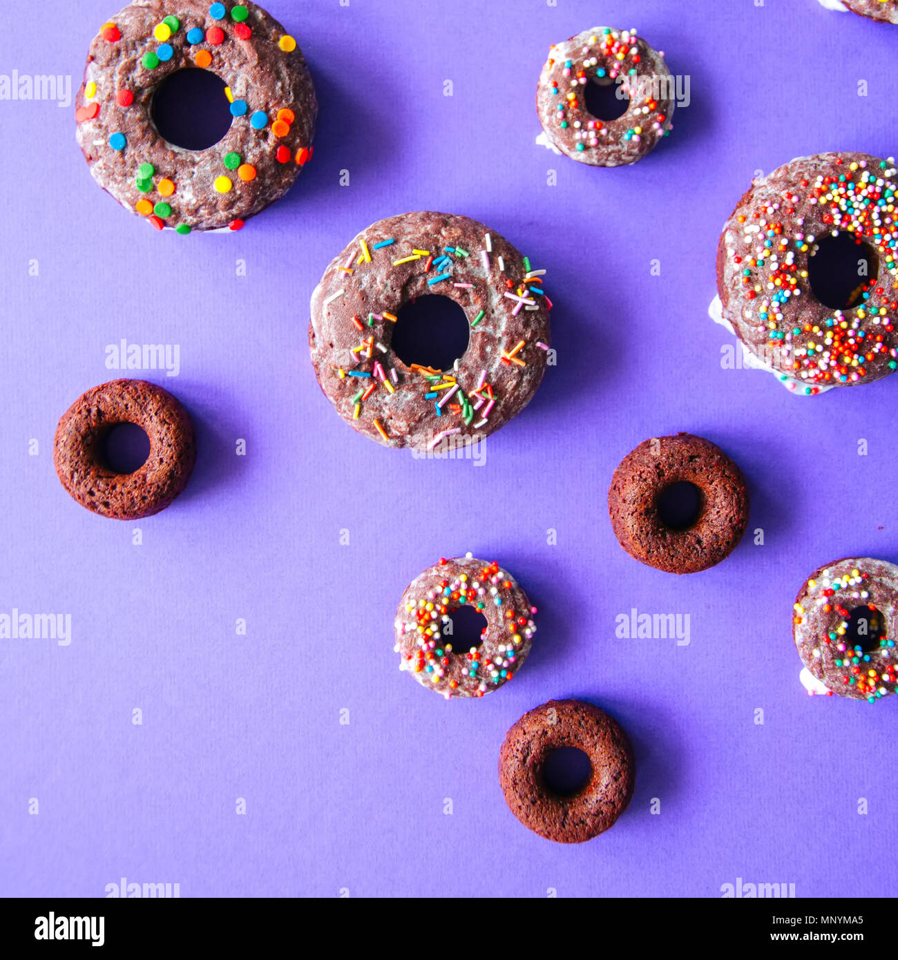 Chocolate baked doughnuts on a violet background glazed and decorated ...