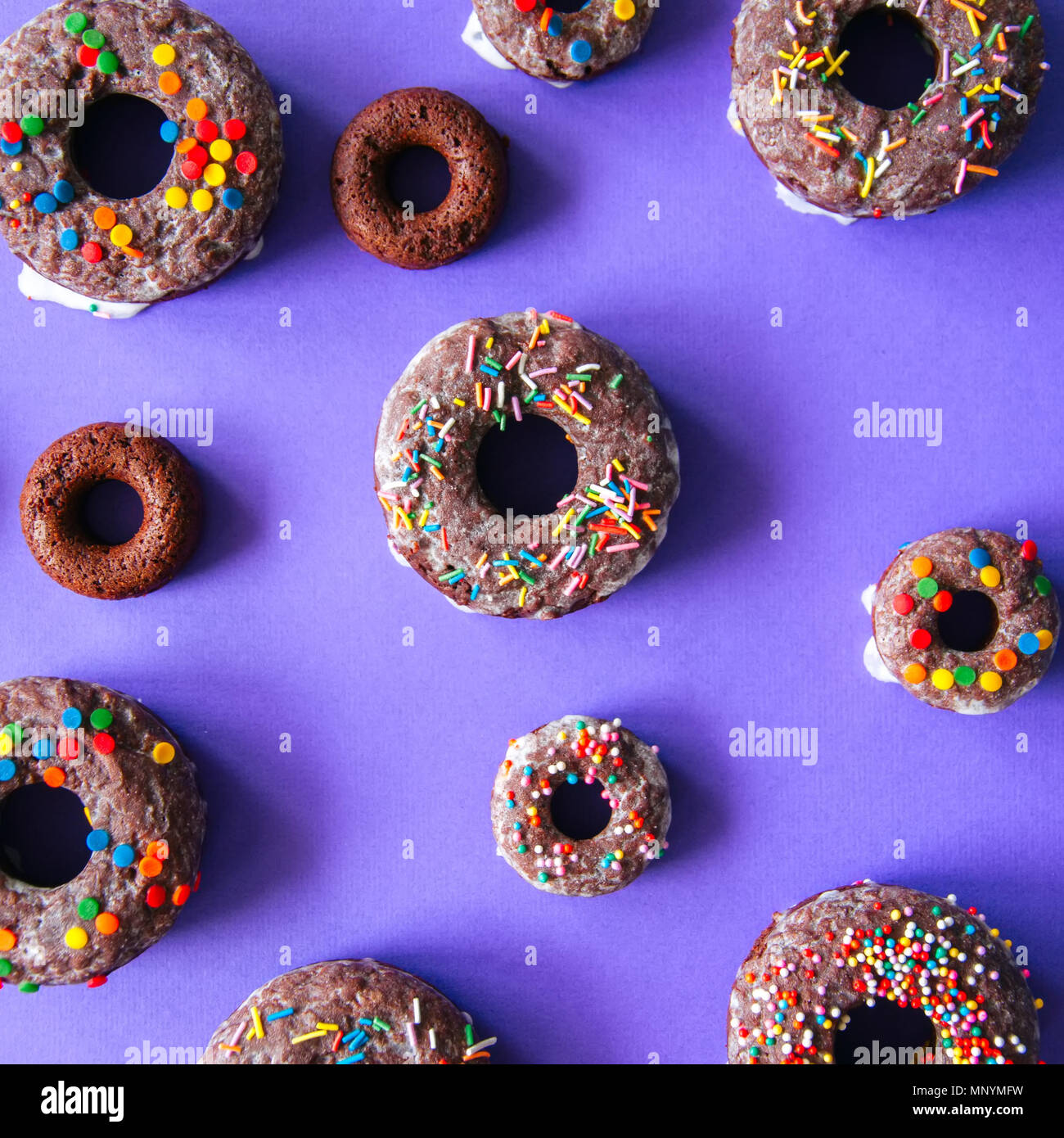 Chocolate baked doughnuts on a violet background glazed and decorated ...