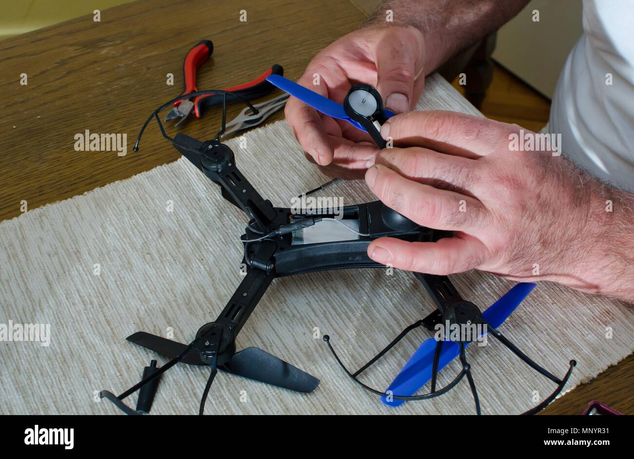 hands of man repairing small black drone with blue propeller Stock ...
