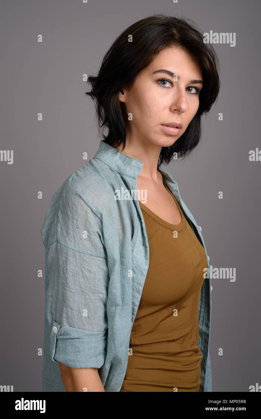 Young beautiful woman against gray background Stock Photo - Alamy