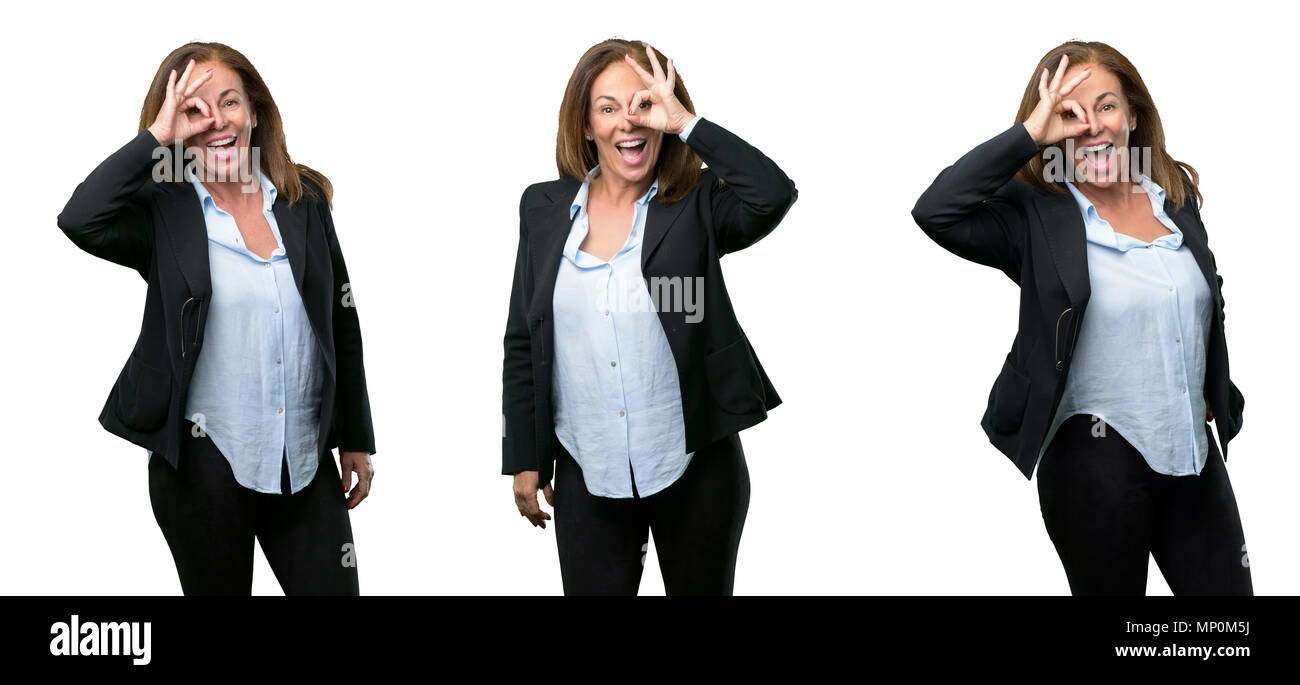 Middle age business woman looking at camera through her fingers in ok ...