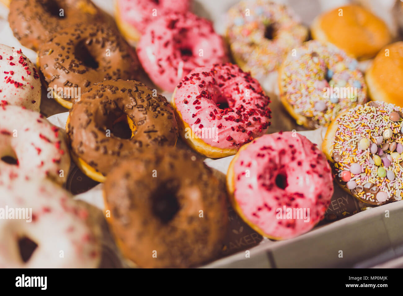 mixed flavours donuts in store display with colorful icinngs and ...