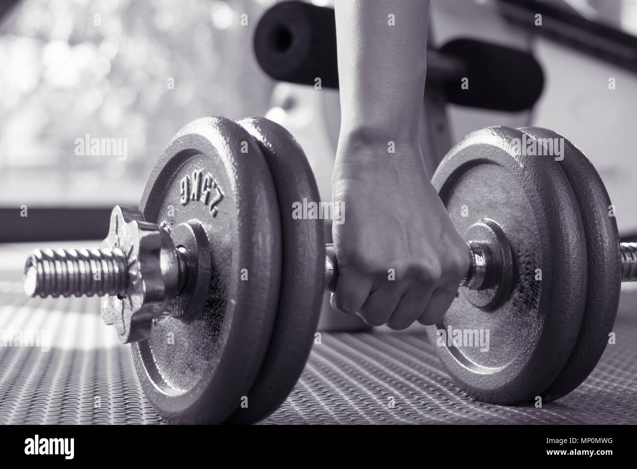black and white image of women hand lifting the steel dumbbell in a gym ...