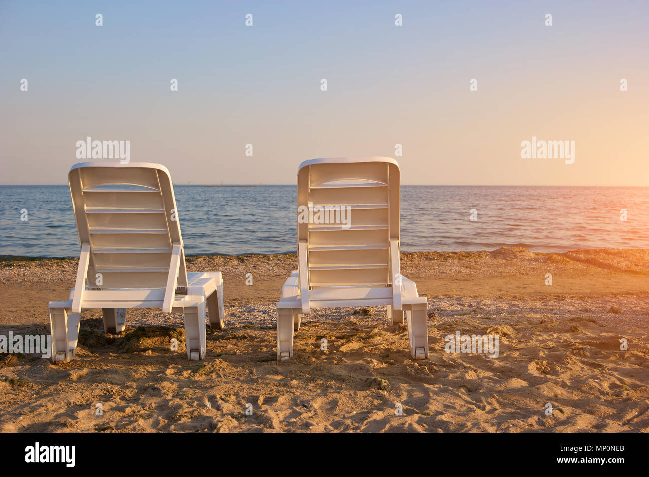 Two chaise lounges on sand on seashore, rear view Stock Photo - Alamy