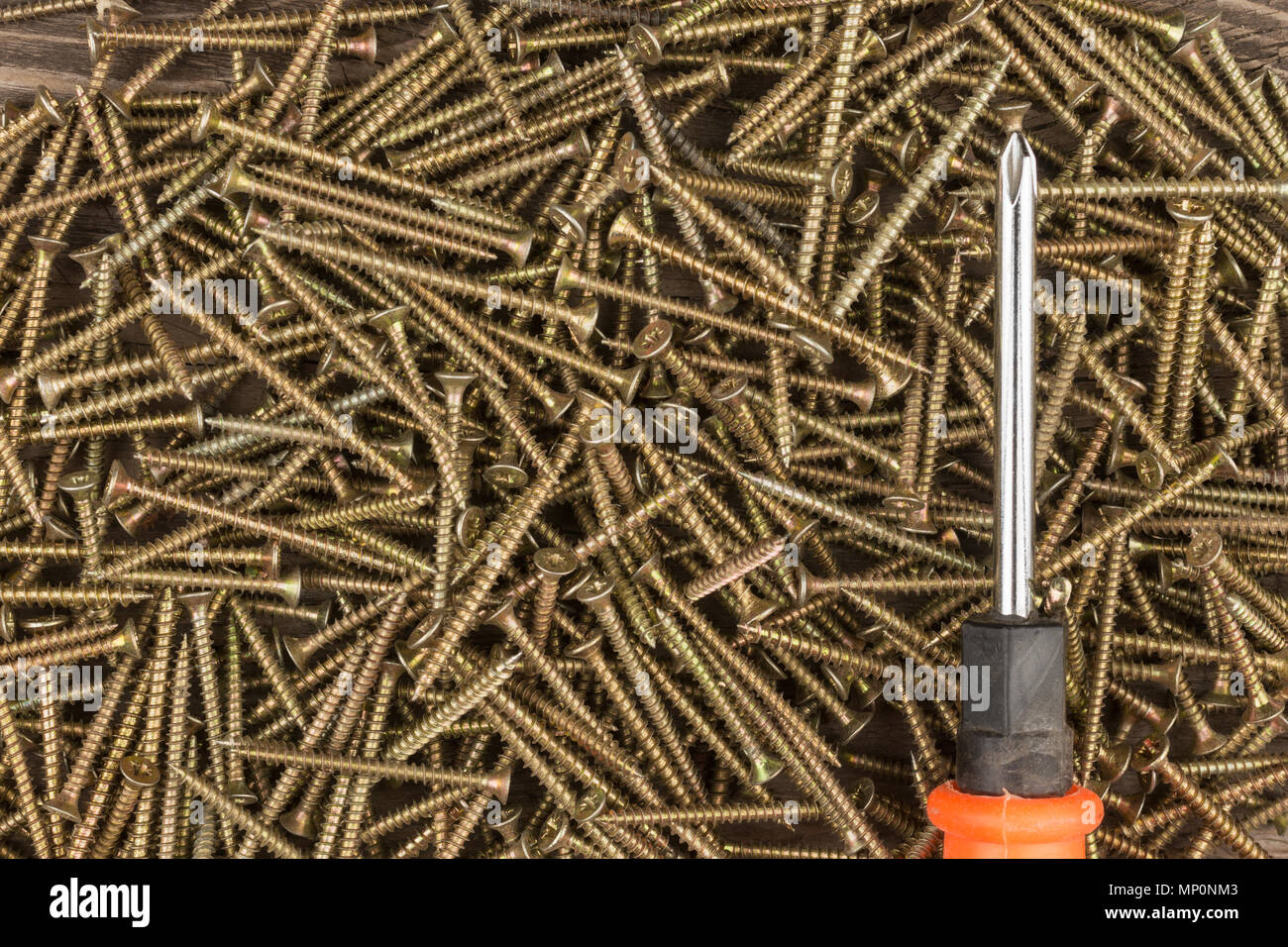 Orange screwdriver lying on the background of screws. View from above ...
