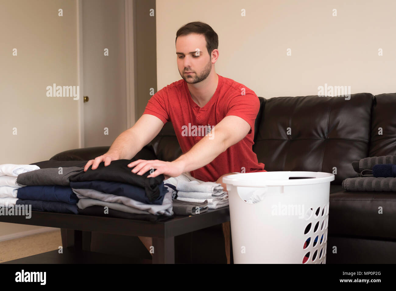 Handsome Man folding laundry on a sofa Stock Photo - Alamy