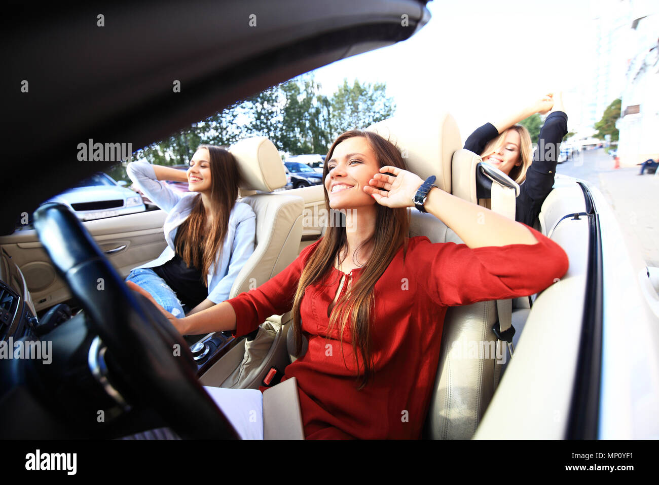three girls driving in a convertible car and having fun Stock Photo - Alamy