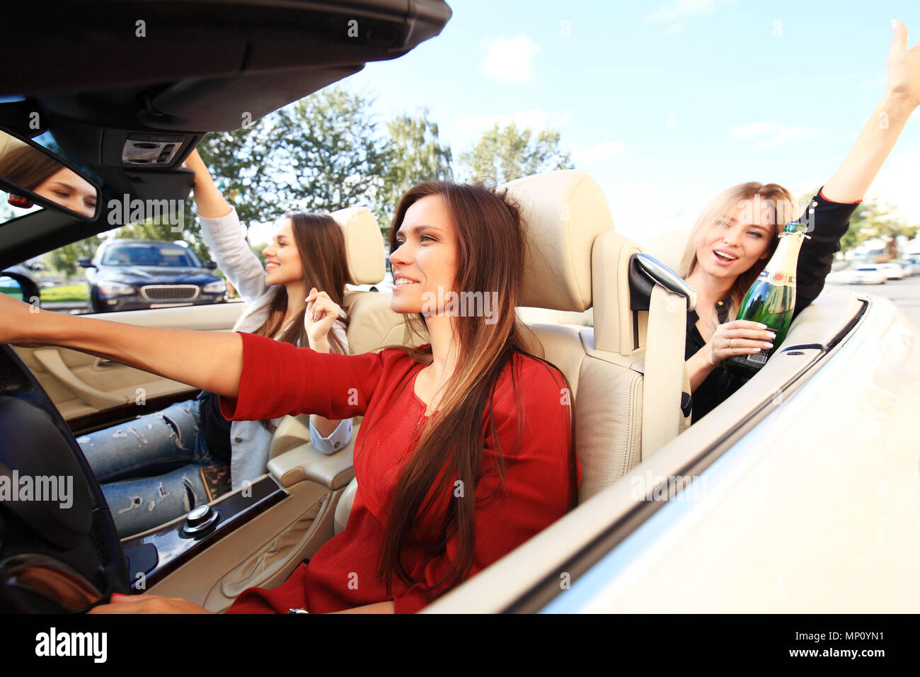 three girls driving in a convertible car and having fun Stock Photo - Alamy