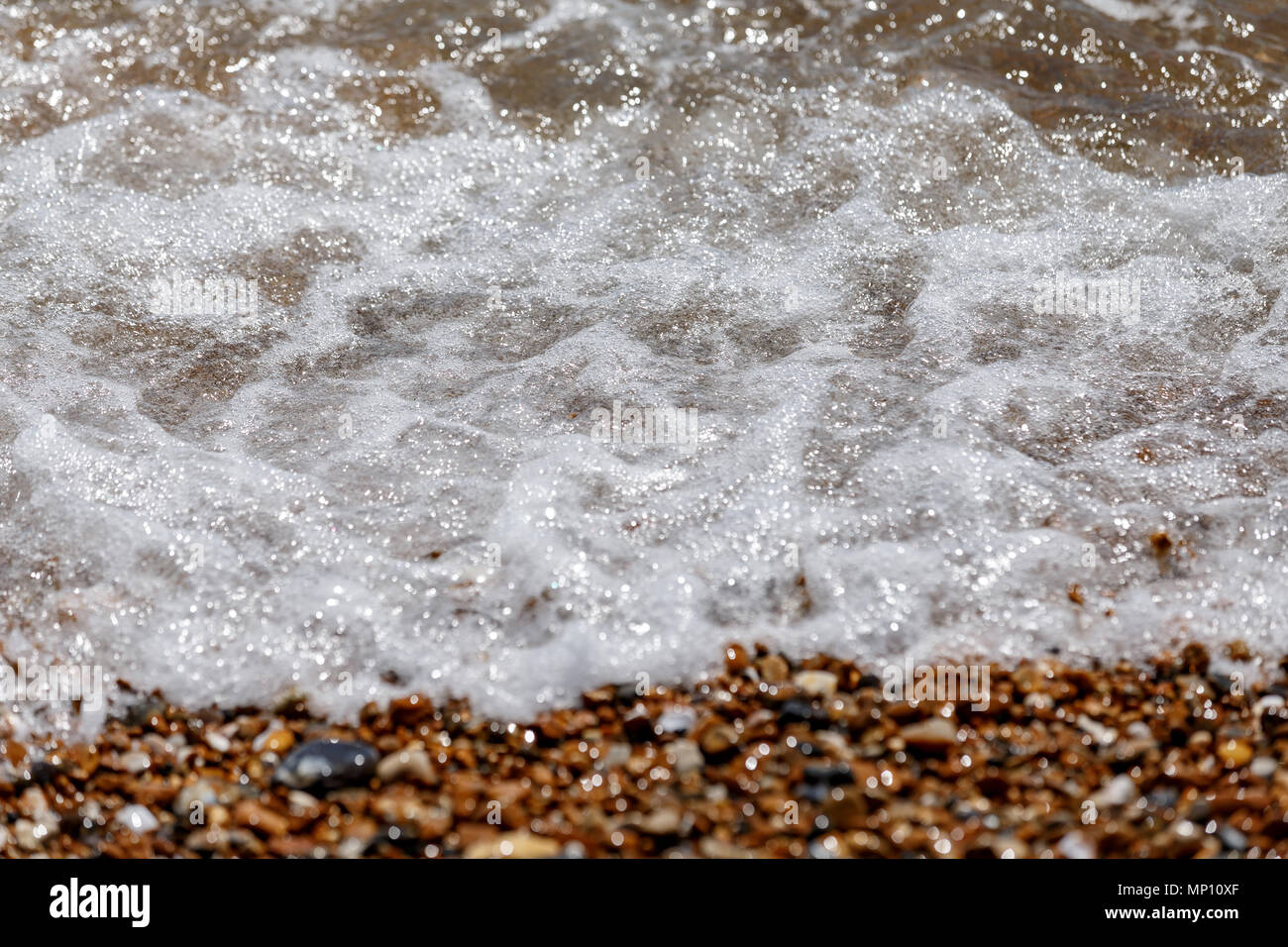 Sea waves landing on the coast of a shingle beach in the United Kingdom ...