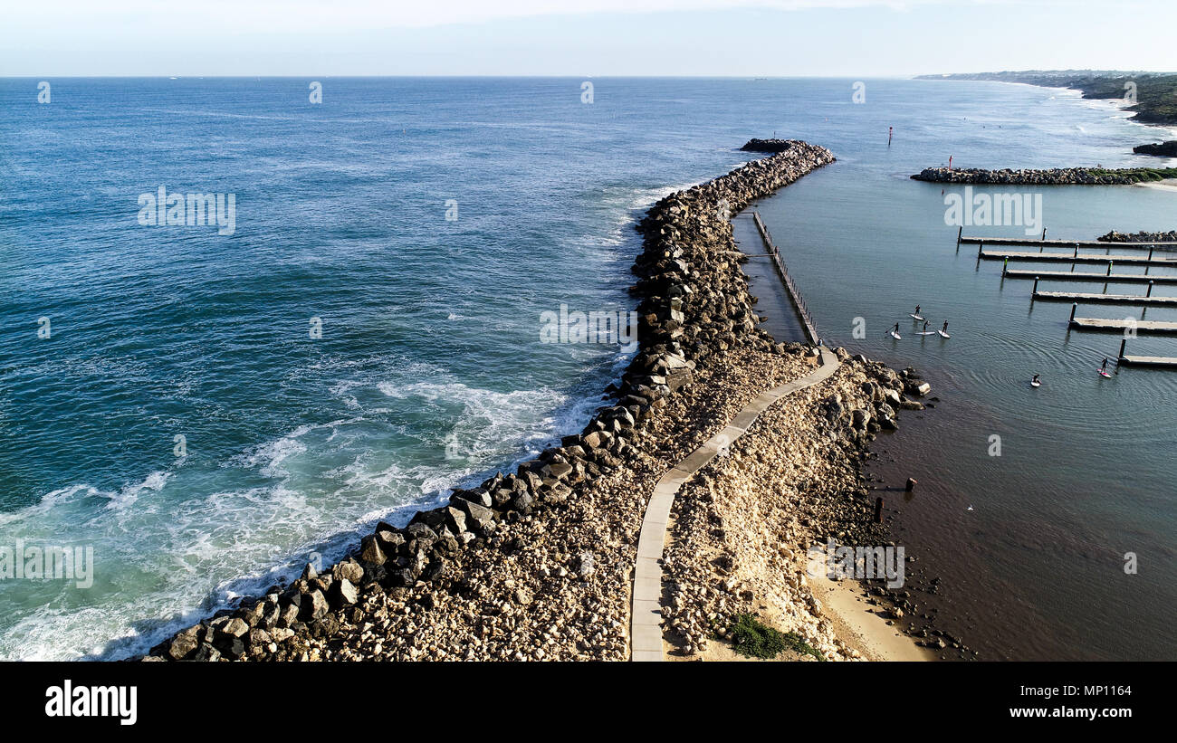 Aerial view of rock sea wall boat harbour with stand up paddle boarders ...