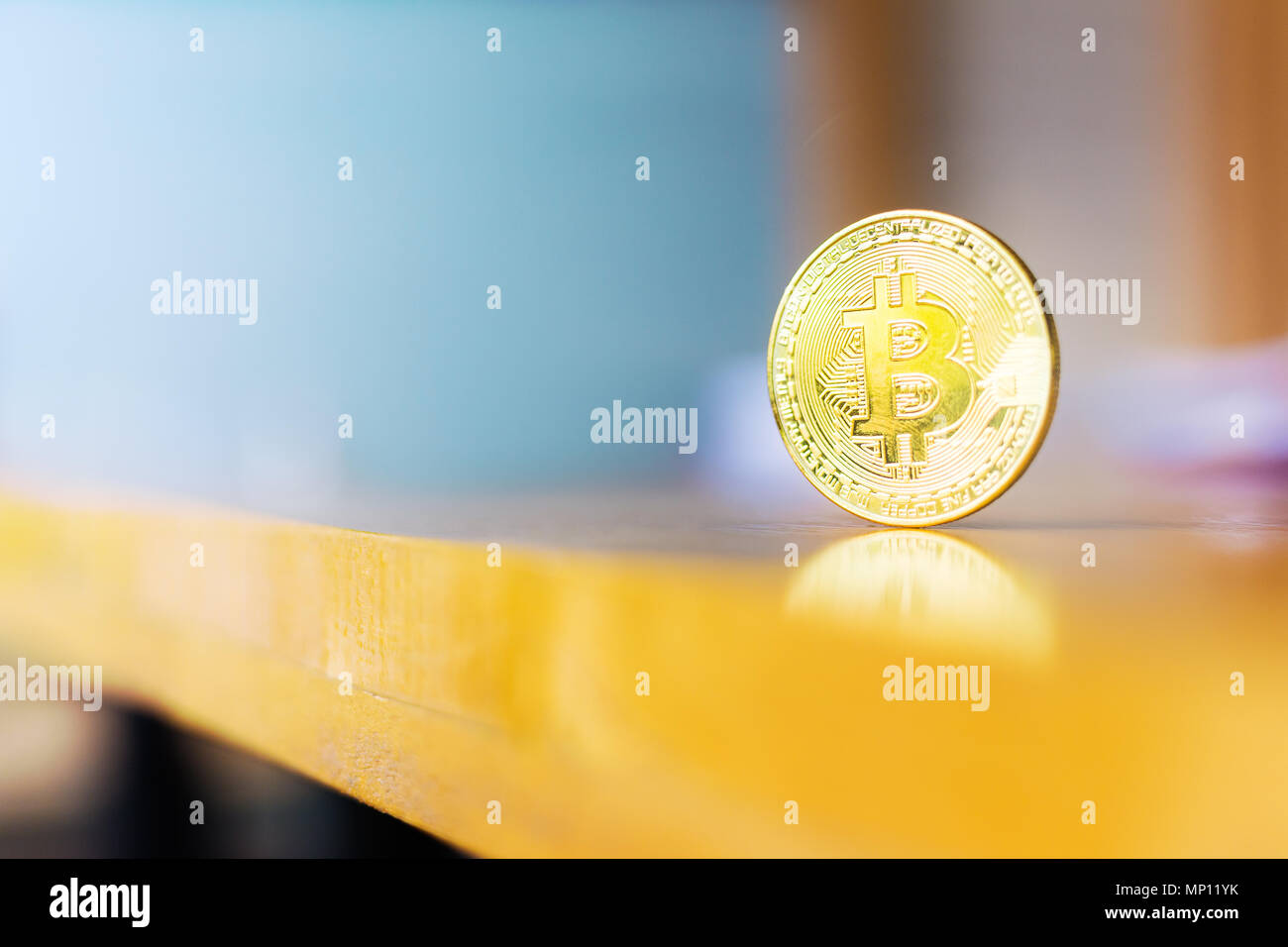 A shiny golden color Bitcoin, cryptocurrency coin, standing on wood ...