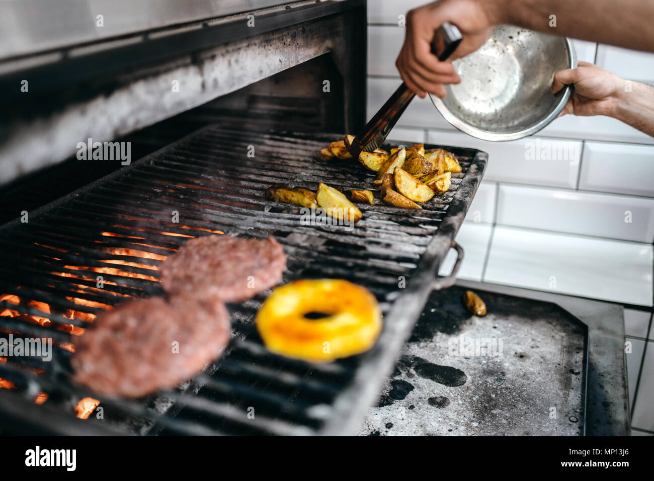 Male cook prepares grilled potato, cooking on grill oven. Fast food ...