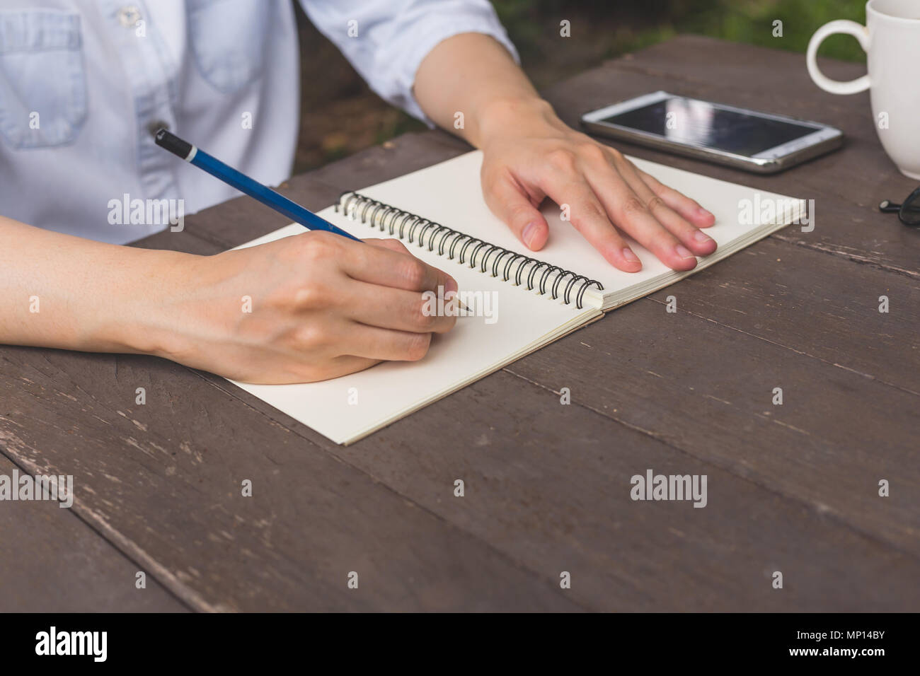 Hand woman writing notebook on wood table with cup coffee and phone ...