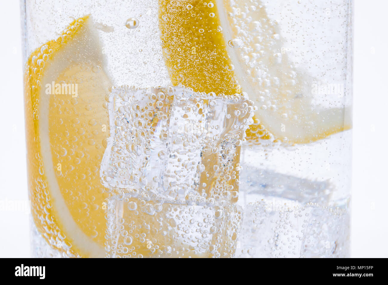 Slices of fresh juicy yellow lemon with ice in water Stock Photo - Alamy