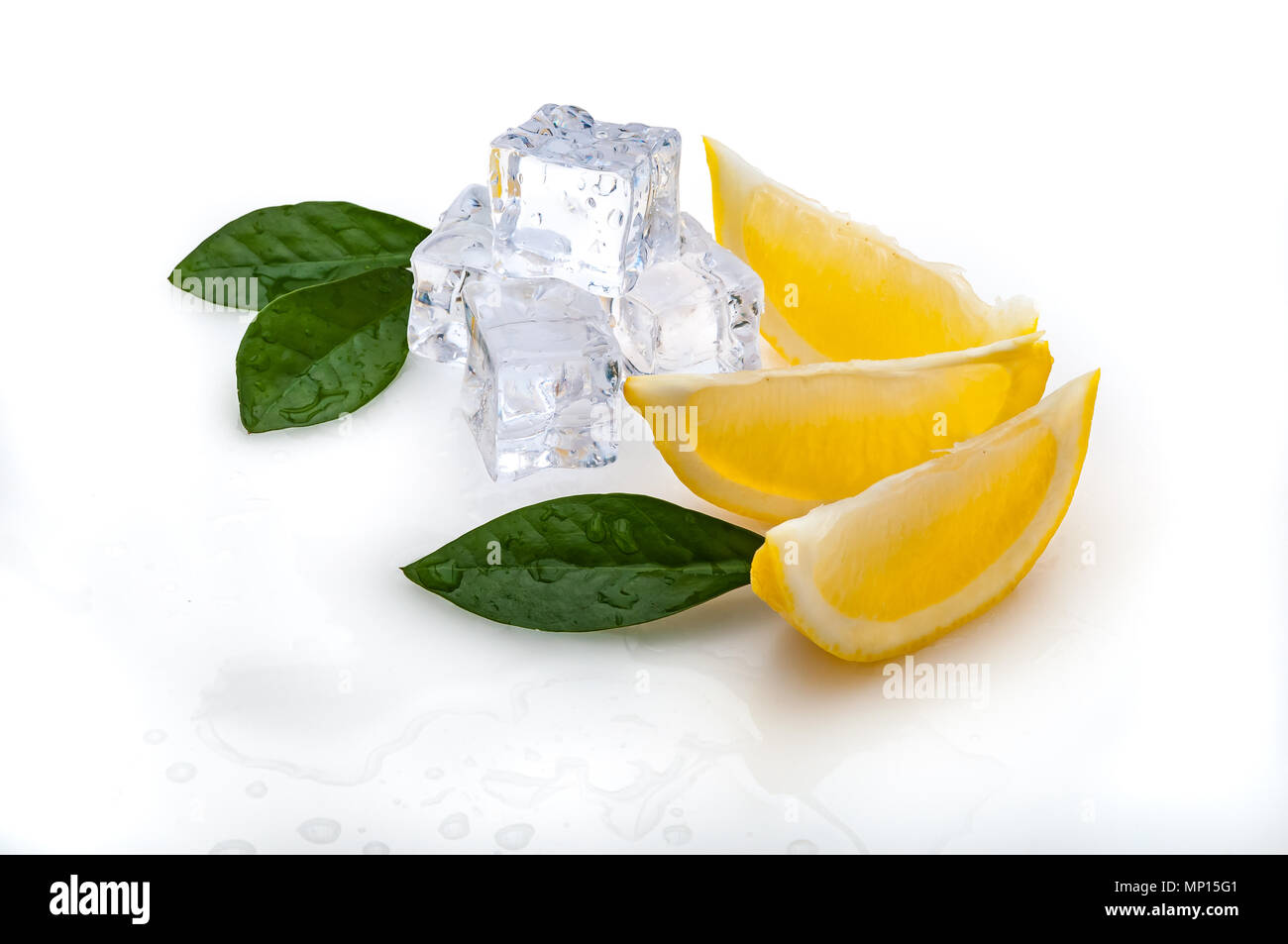 three slices of fresh lemon and green leaves, cubes of cold ice, on ...