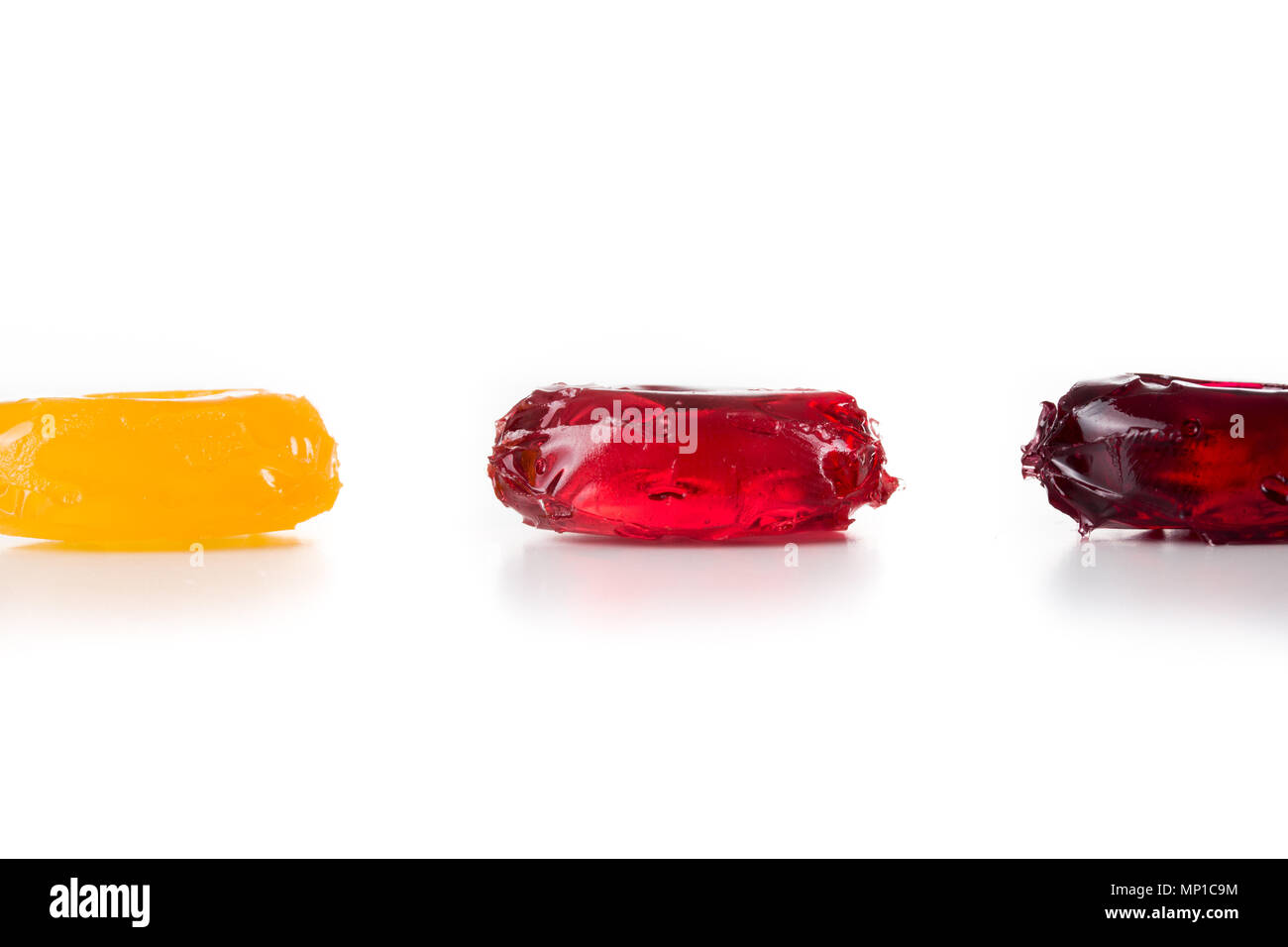 three coloured candies in side view, in front of a white background ...