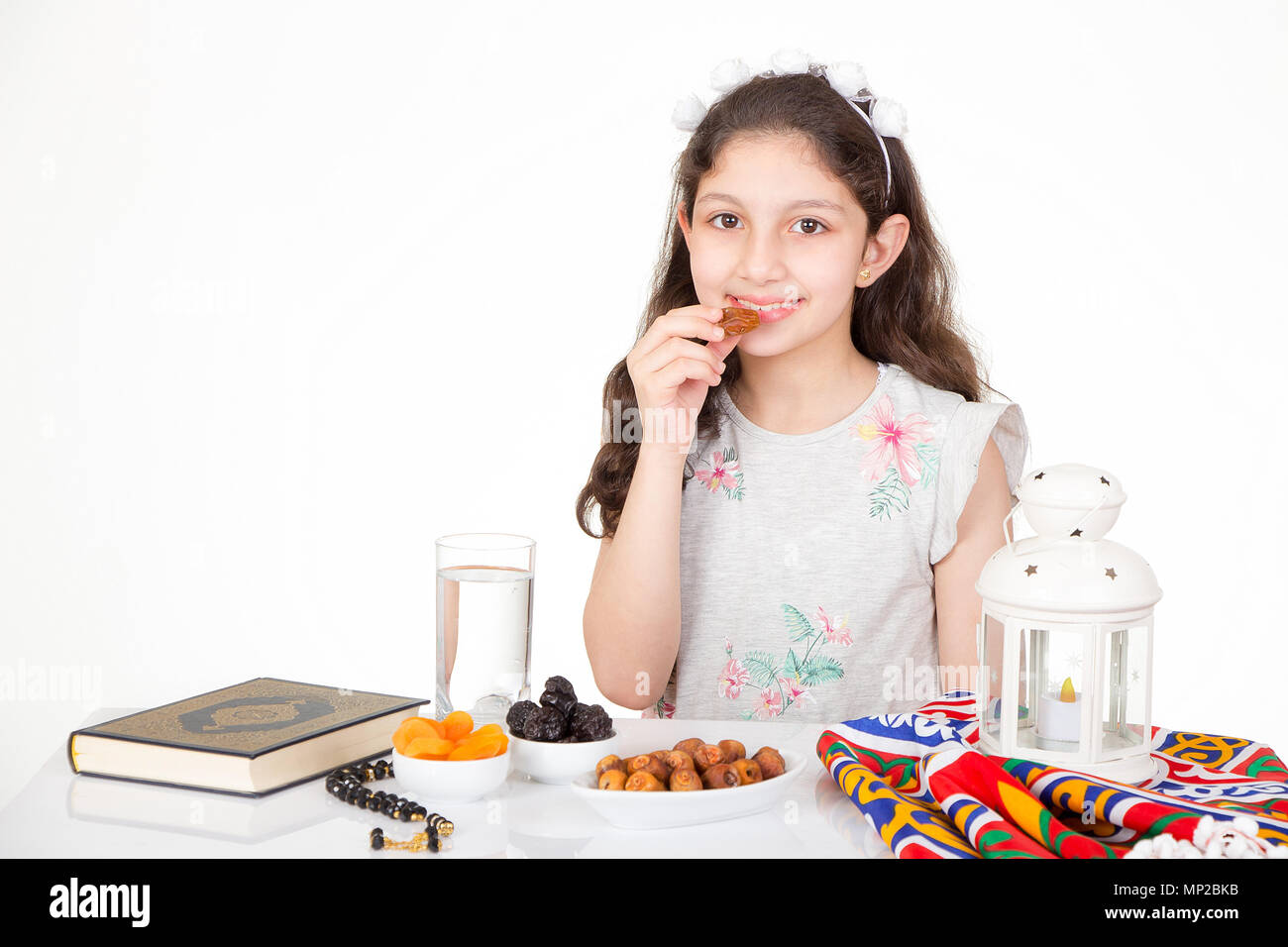 Happy young Muslim girl fasting Ramadan , eating dates, sitting infront ...