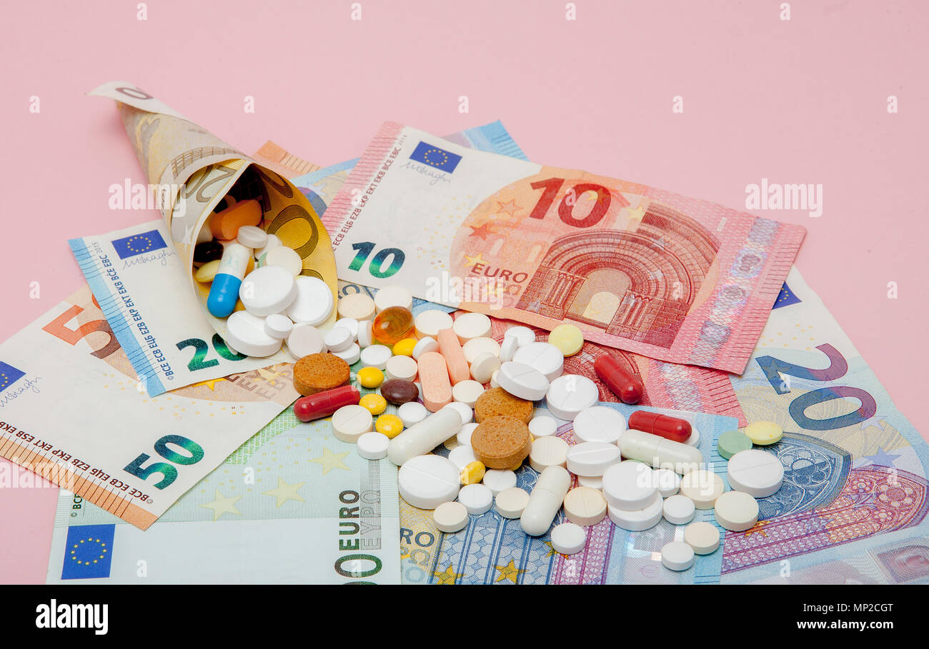 The tablets wrapped in euro with euro banknotes on a pink background ...