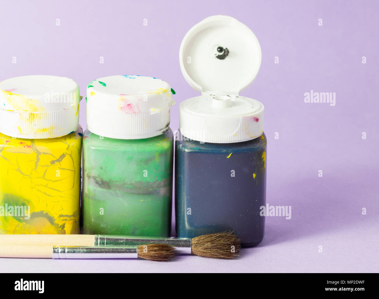Old and used paint containers isolated on a lilac background. Concept ...