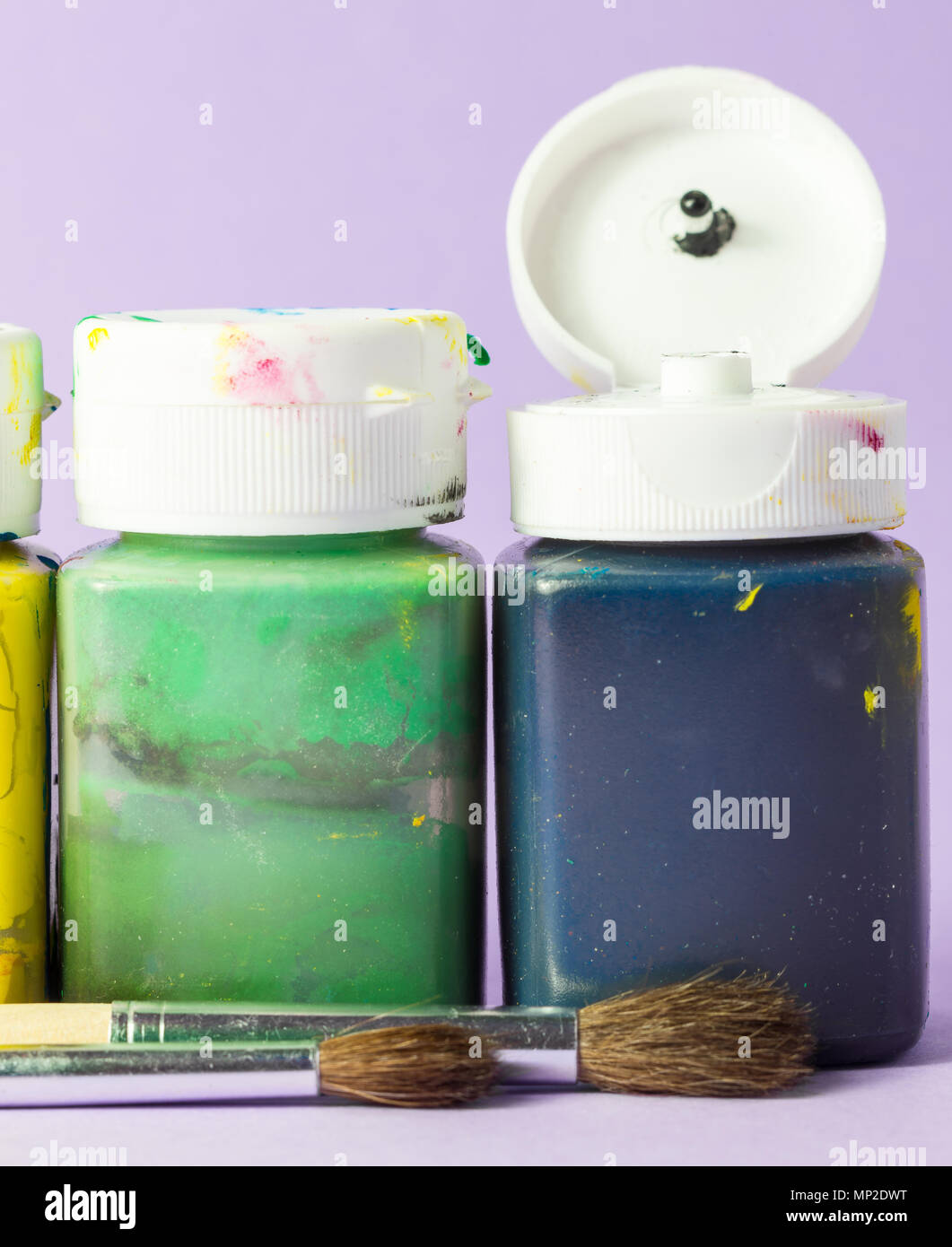 Old and used paint containers isolated on a lilac background. Concept ...