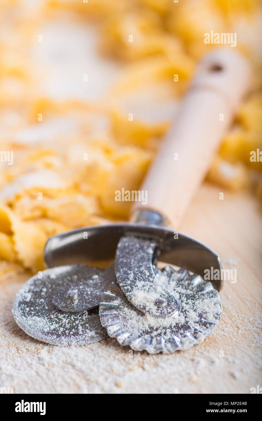 Fresh egg pasta and a dough cutter wheel to prepare it Stock Photo - Alamy